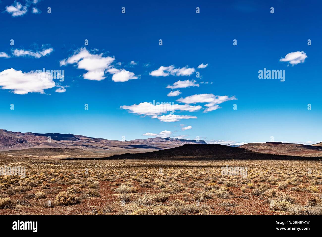 Open desert field with mountains and a cloudy blue sky in the ...