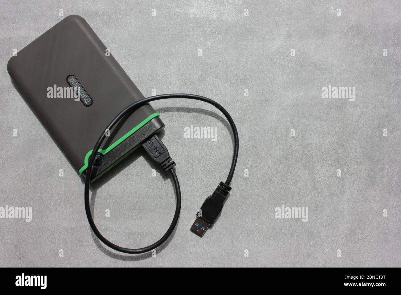 Gray and green external hard drive for backup with USB cable on gray ...