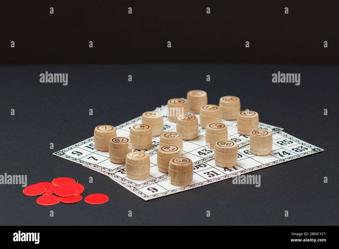 Board game lotto. Wooden lotto barrels with game cards and red chips on ...