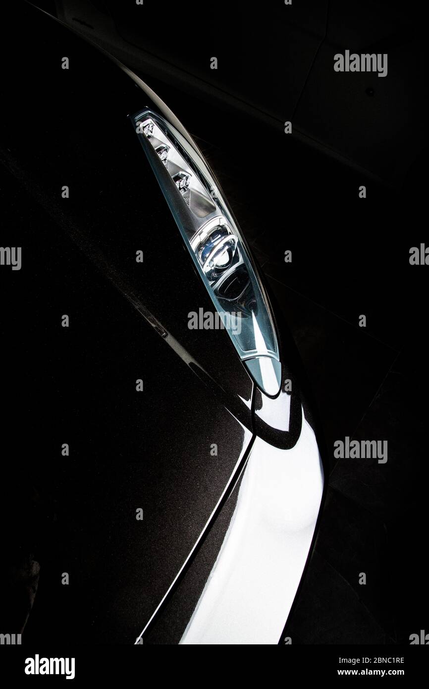 Vertical closeup of the headlight of a luxury car under the lights ...