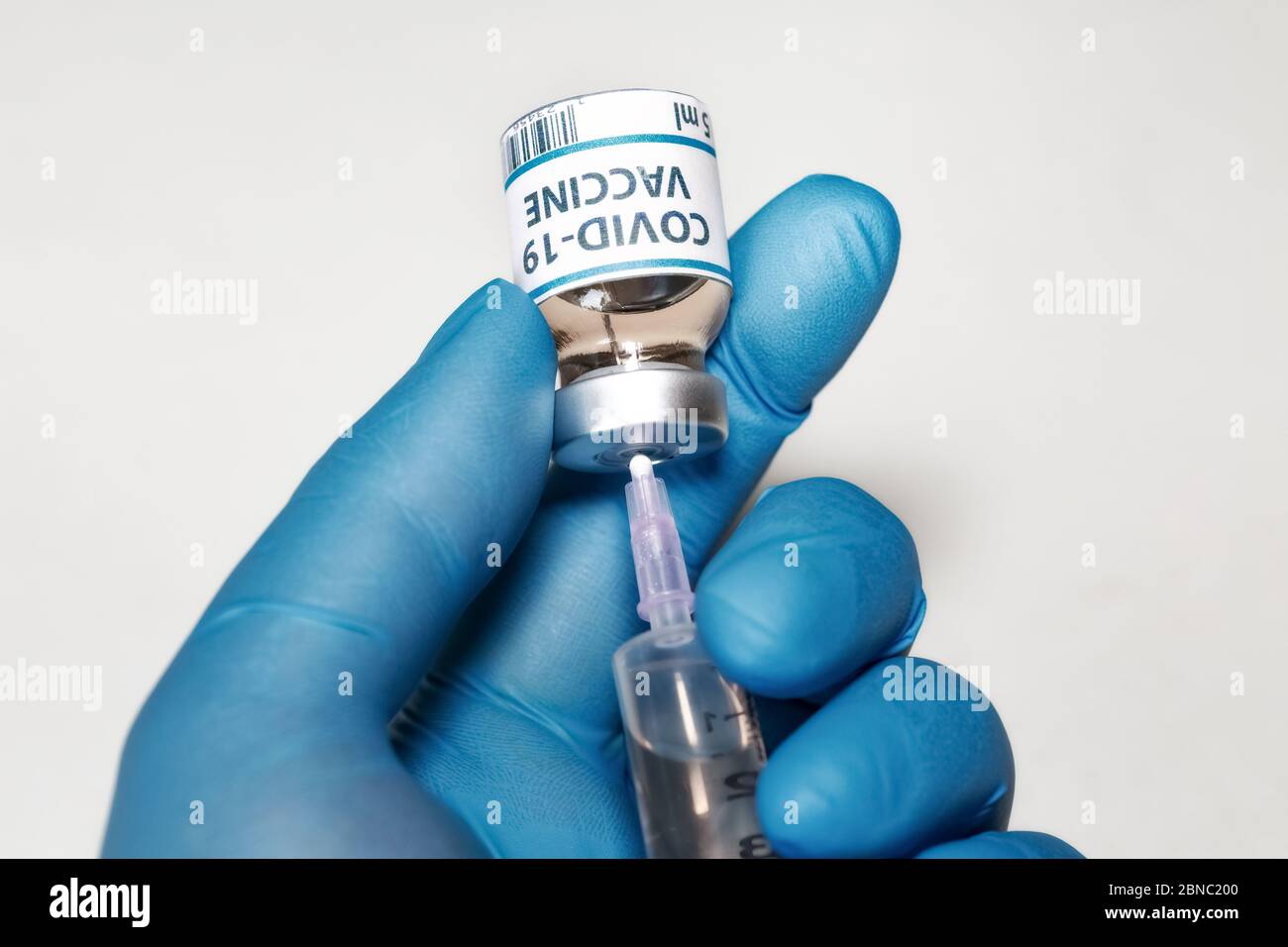 Doctor hands in medical gloves hold a vaccine bottle vial while ...