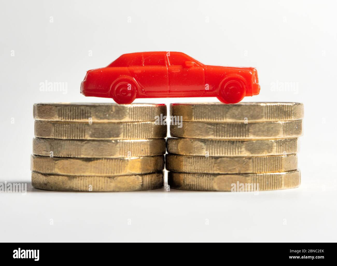 A small red plastic car on stacks of one pound coins,car insurance ...
