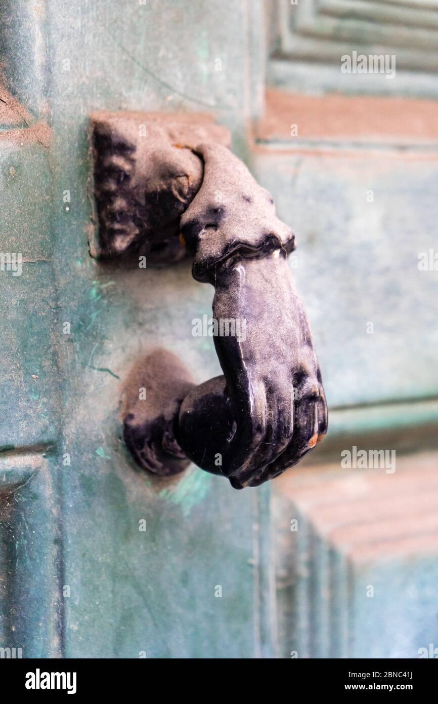 Closeup vertical shot of an old door handle in the shape of a human ...