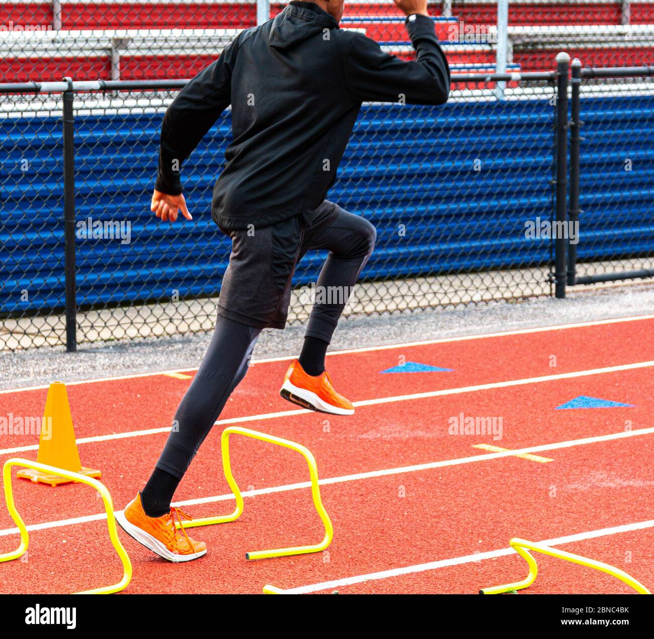 Side view of a black sprinter performing speed and flexibility drills ...