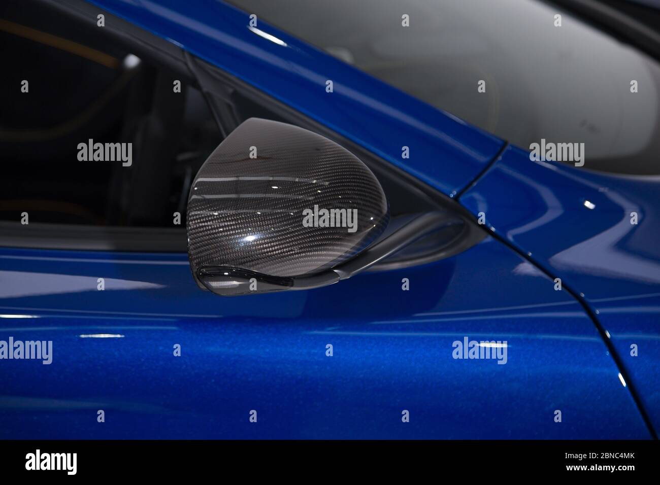 Closeup shot of the mirror of a shiny blue modern car under the lights ...