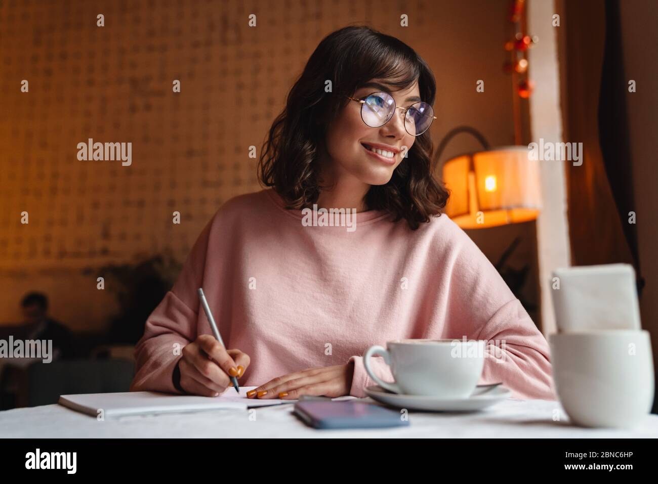 Photo of a beautiful pretty happy brunette young woman indoors in cafe ...
