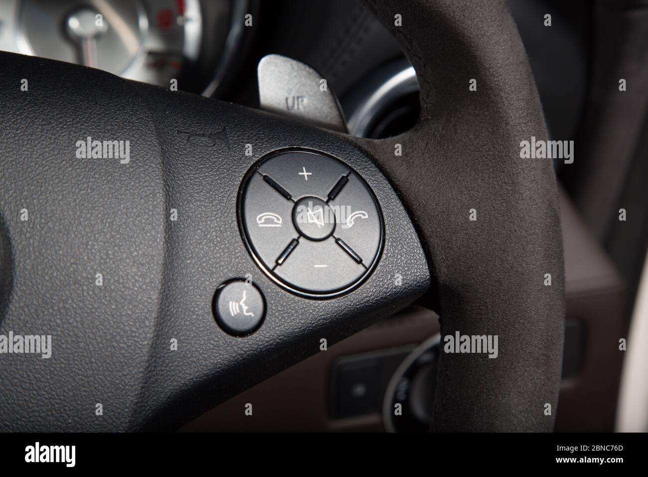 Closeup of control buttons on the steering wheel of a luxury car under ...