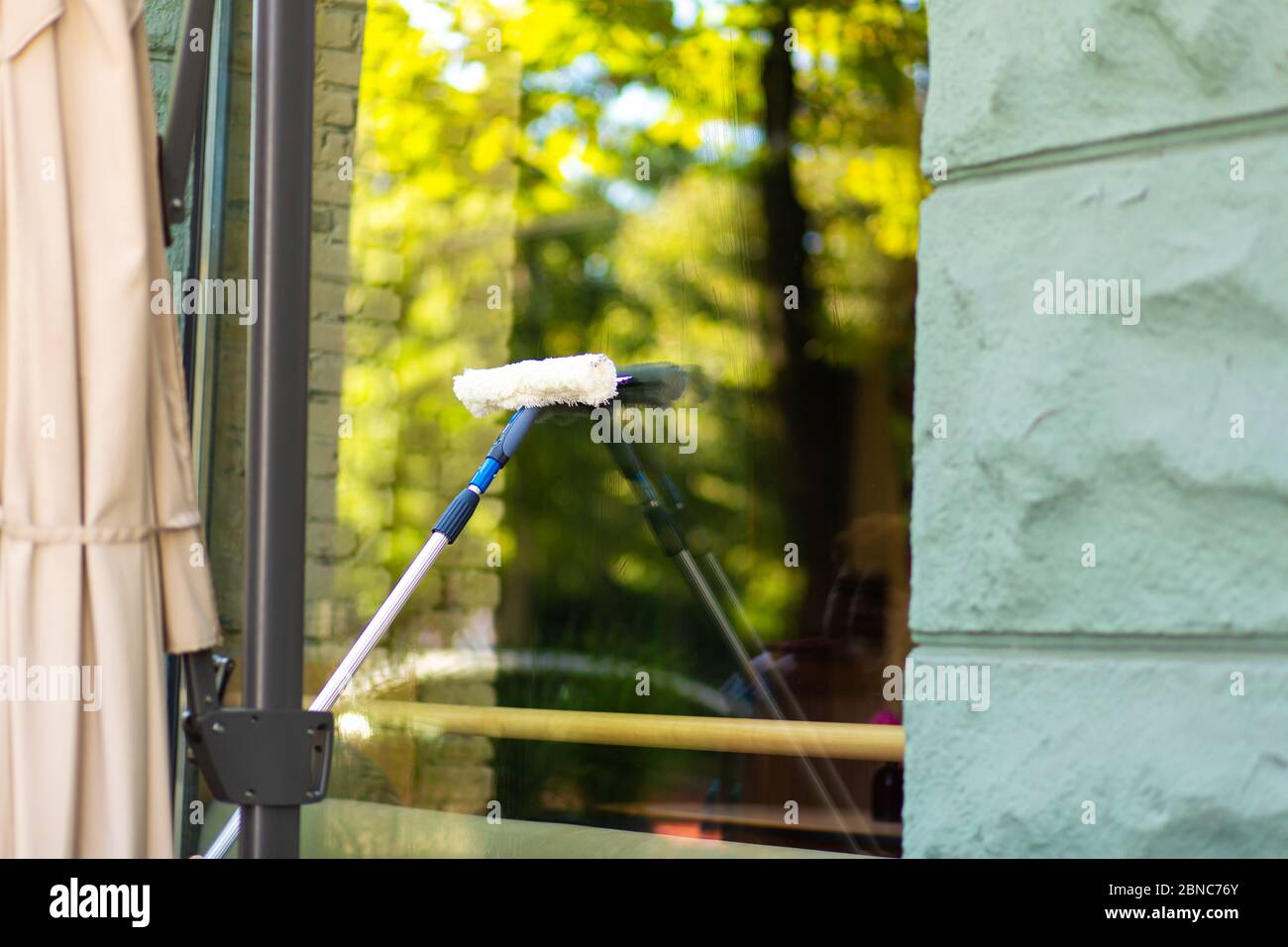 An employee washes a large stained-glass window of the store. Washes a ...