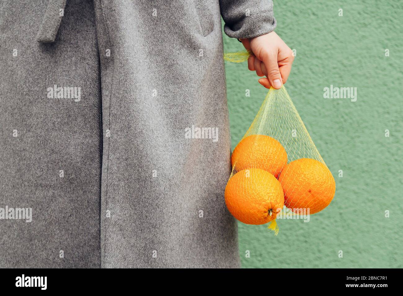 Woman Holds Fresh Oranges in Plastic Mesh Sack over Green Background ...