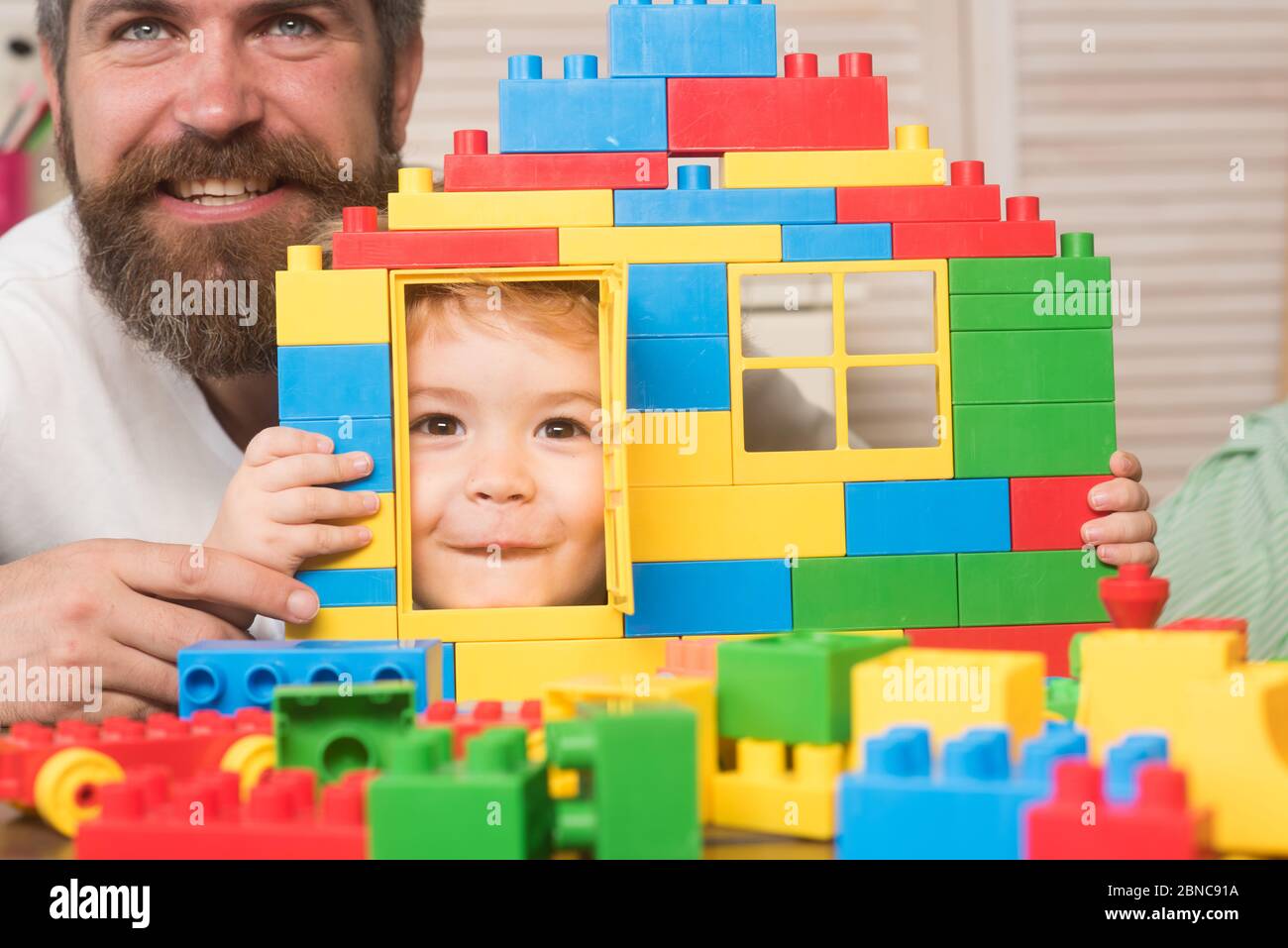 Kid looking through door of toy house made of plastic blocks. Child and ...