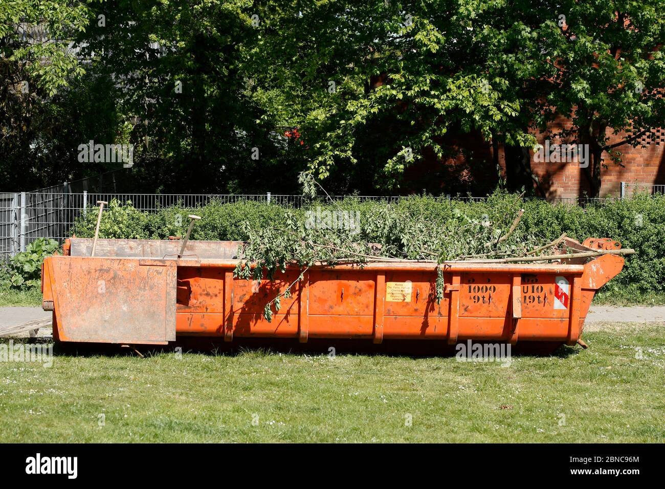 Orange dumpster with plant waste standing in a meadow, Germany, Europe ...