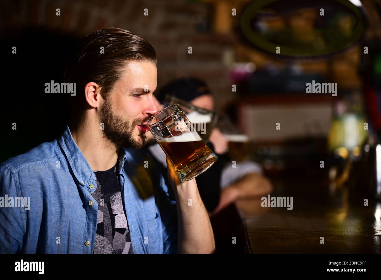 Man drink beer sitting in bar. Friends drink beer together on blurred ...