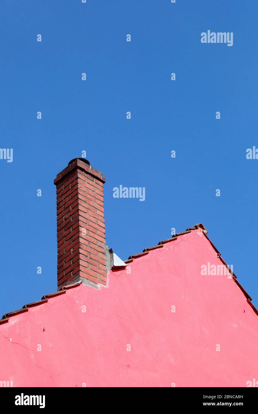 Roof, chimney, pink house wall, roof edge, blue sky Stock Photo - Alamy