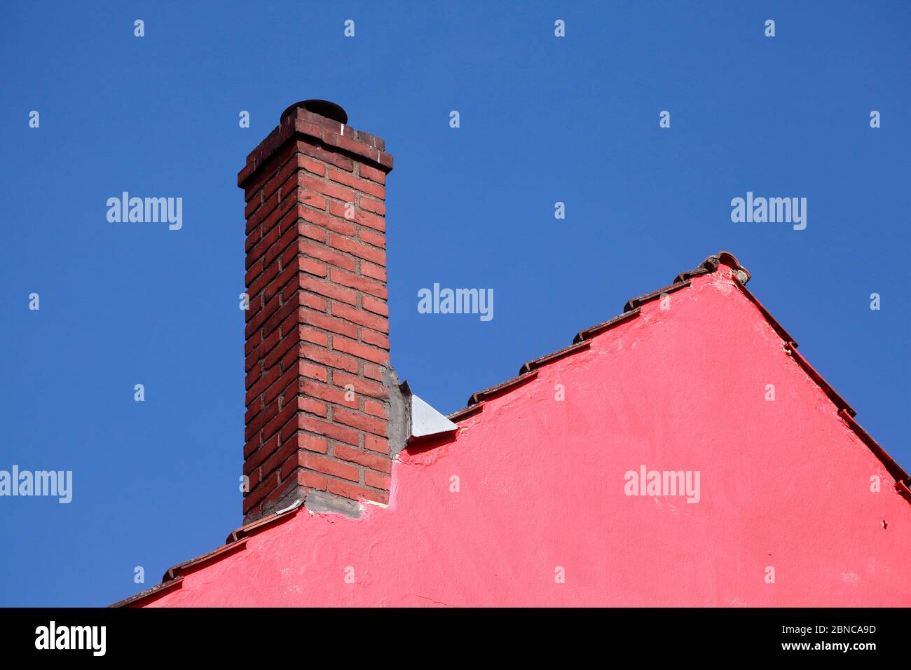 Roof, chimney, pink house wall, roof edge, blue sky Stock Photo - Alamy