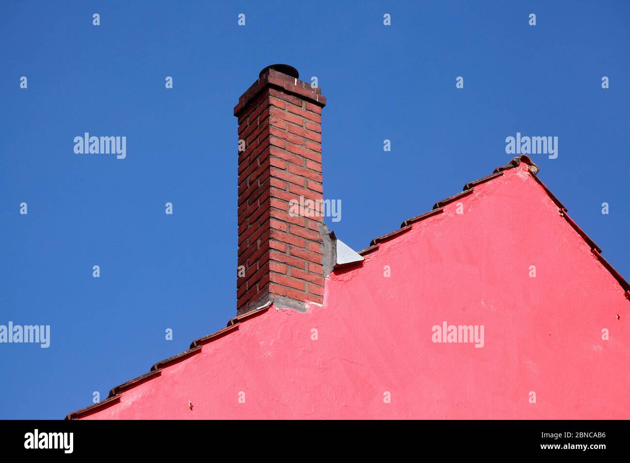 Roof, chimney, pink house wall, roof edge, blue sky Stock Photo - Alamy