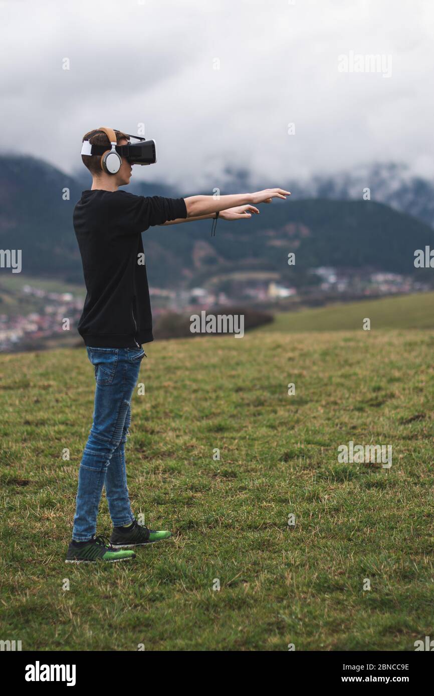 Vertical shot of a teenage male using virtual reality and forgetting ...