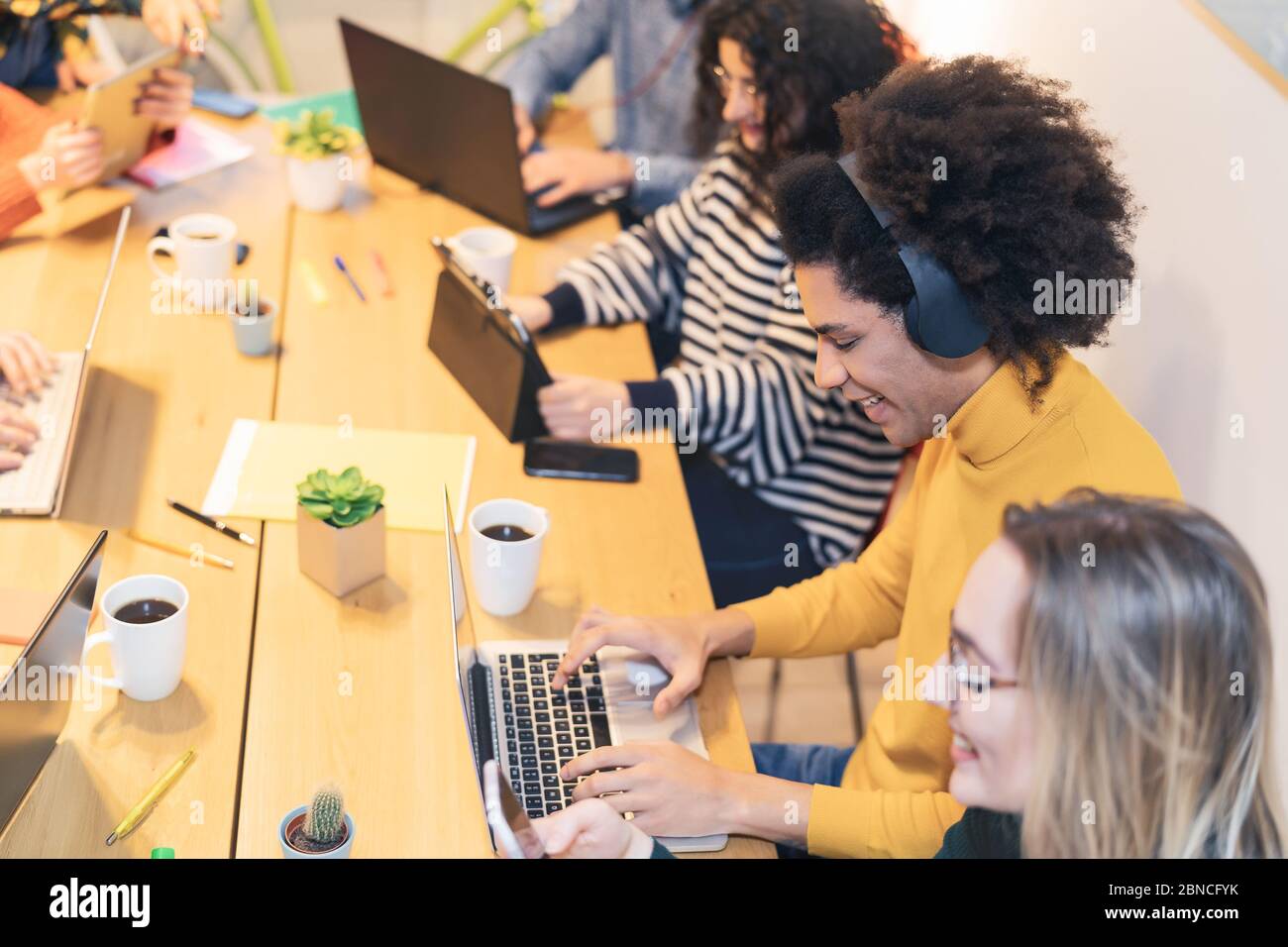 Happy young people working together inside office - Multiracial friends ...