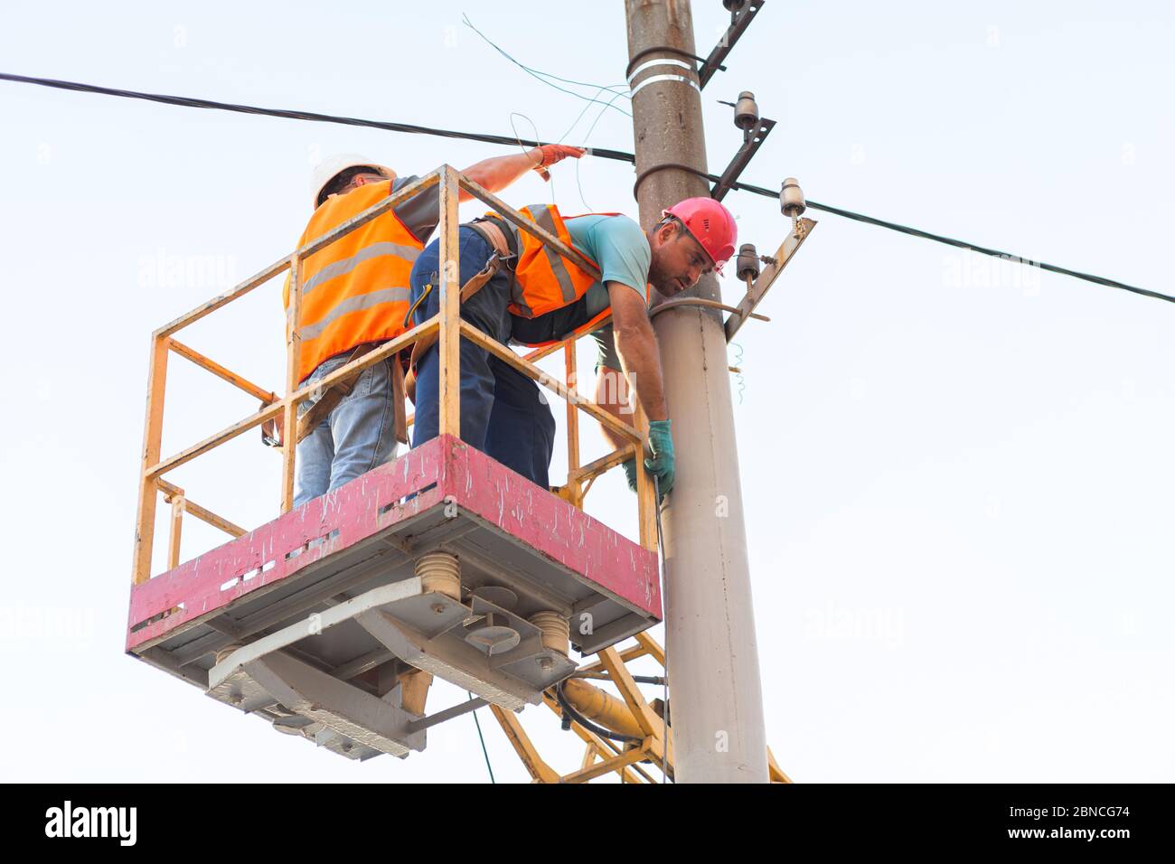 electricians on the pillars install the mount for the power line ...