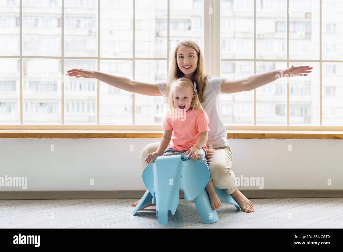 Happy family mother and 3 years old daughter ride on elephant toy Stock ...