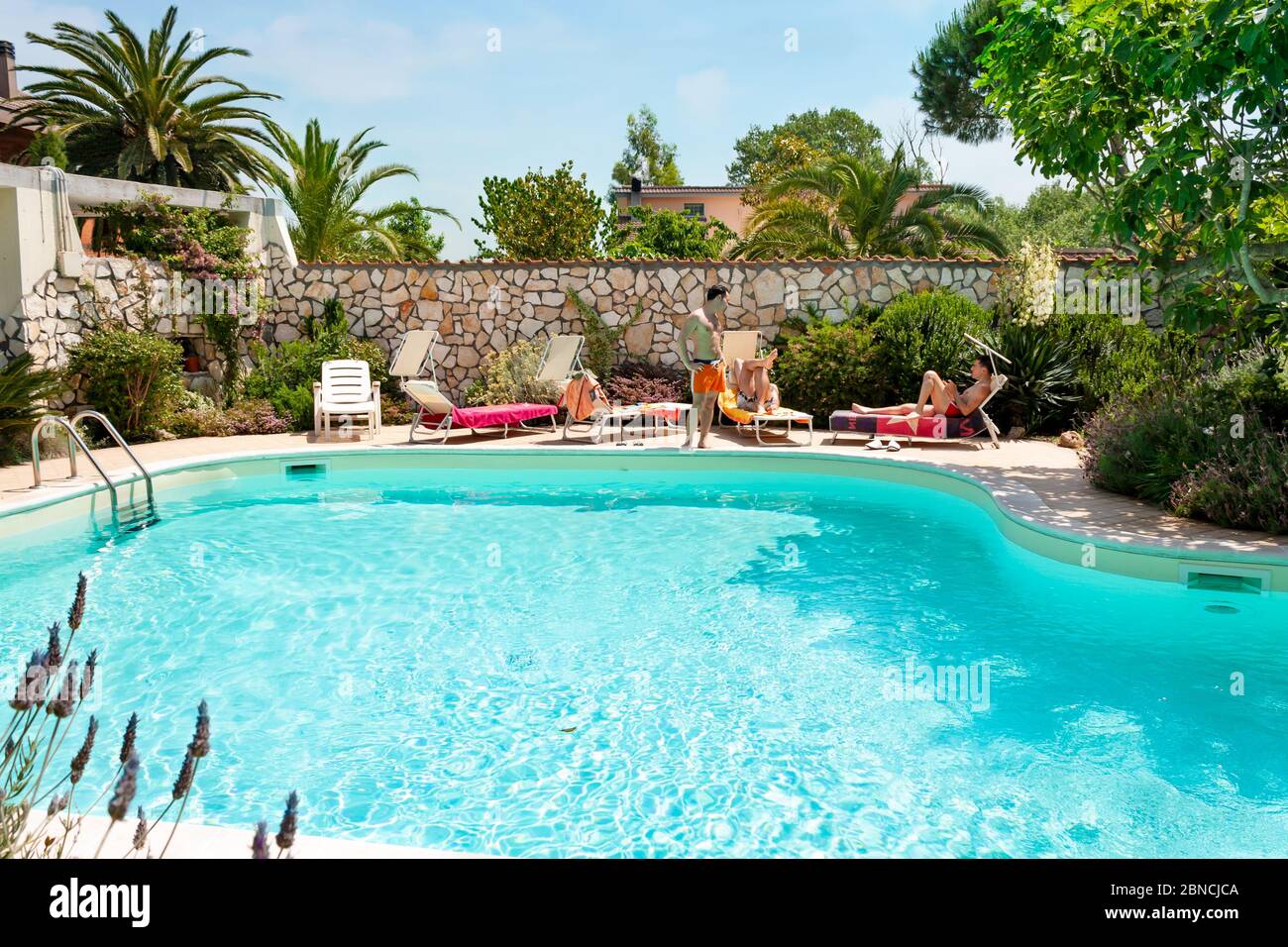 Three Caucasian men sunbathing beside the swimming pool Stock Photo - Alamy