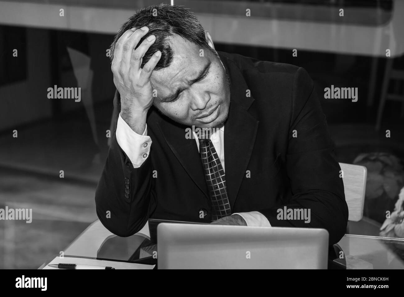 An Asian male businessman is sad and crying in front of the computer ...