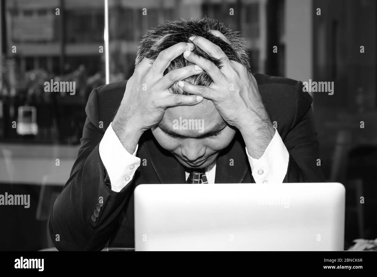An Asian male businessman is sad and crying in front of the computer ...