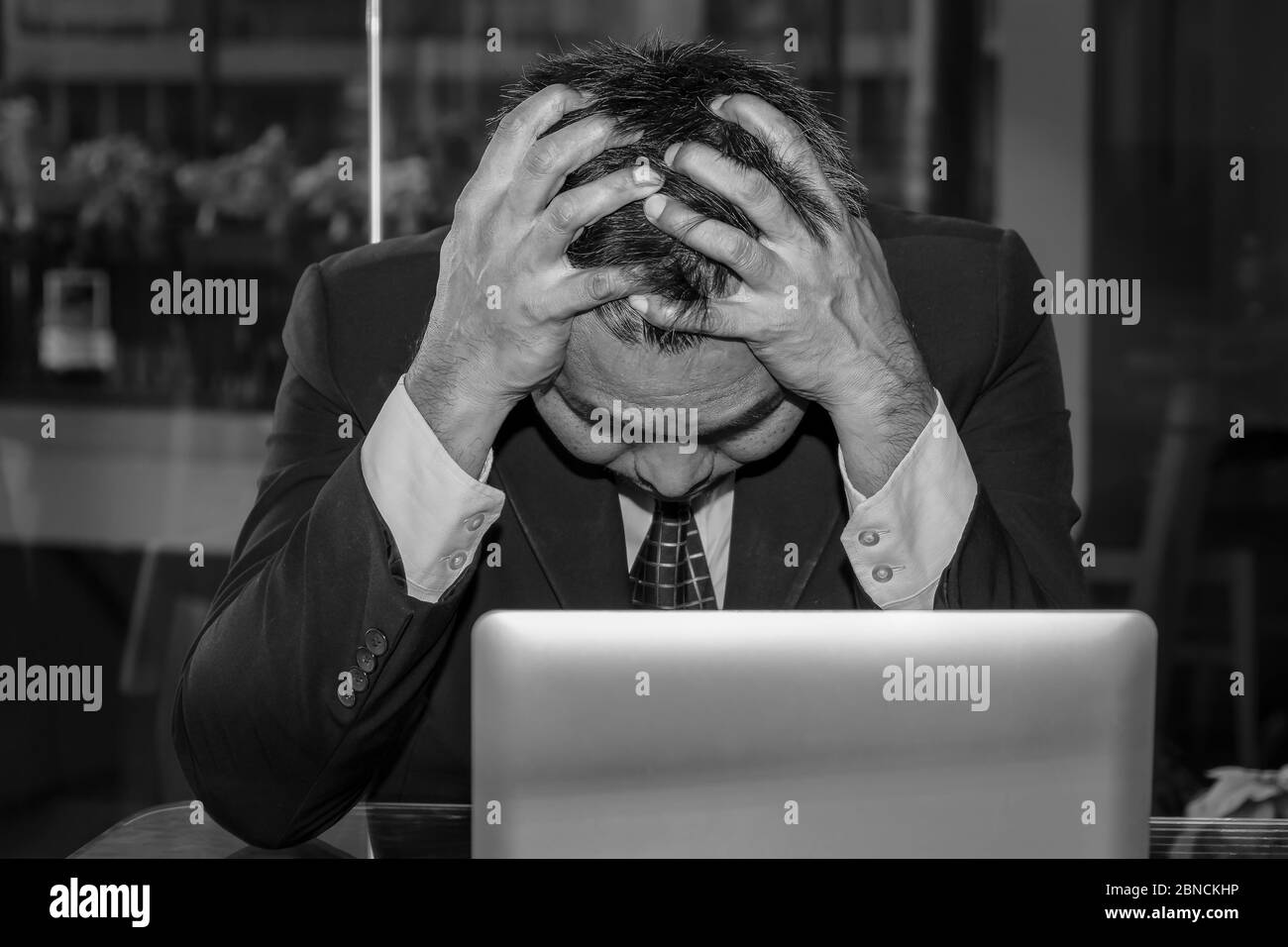 An Asian male businessman is sad and crying in front of the computer ...