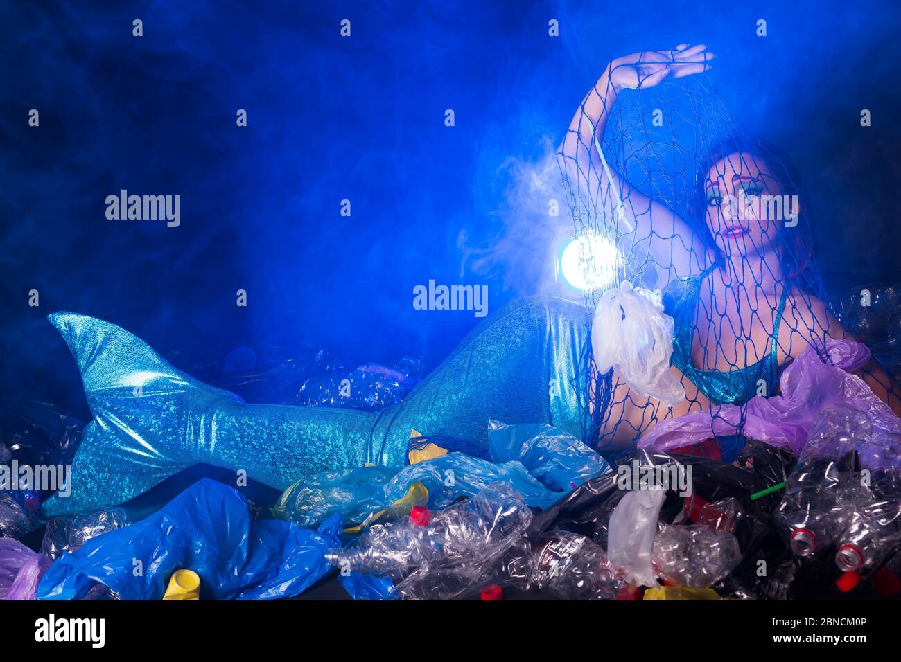 Fantasy mermaid in deep ocean shocked because water pollution. Plastic ...