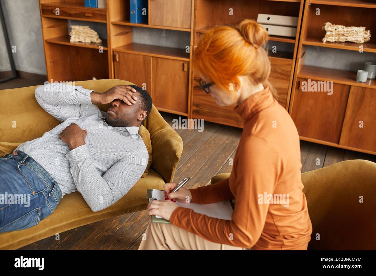 African sad man lying on sofa he talking with his psychologist while ...