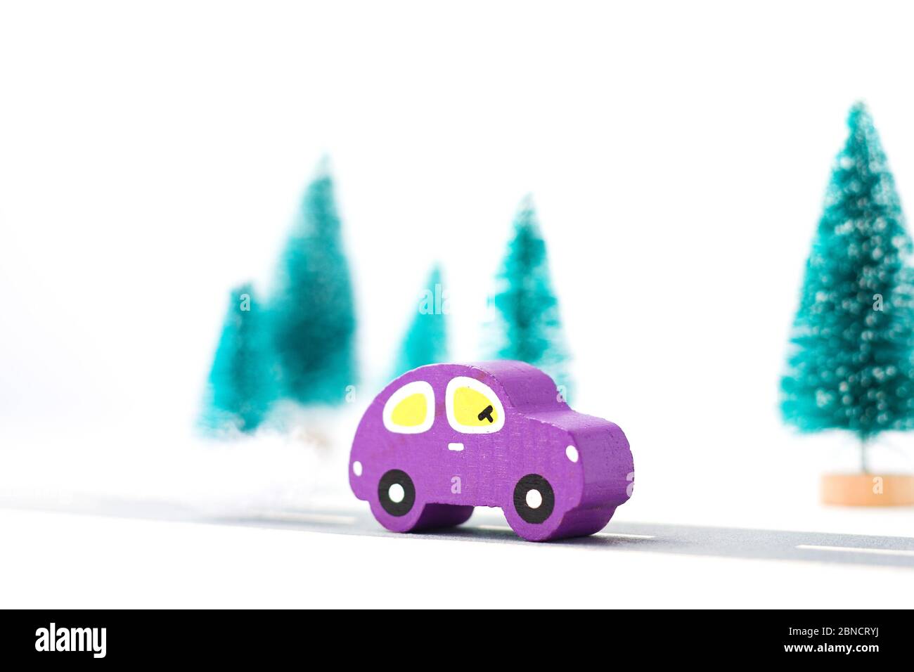 Wooden car on paper road against fir-trees on white background. Traffic ...