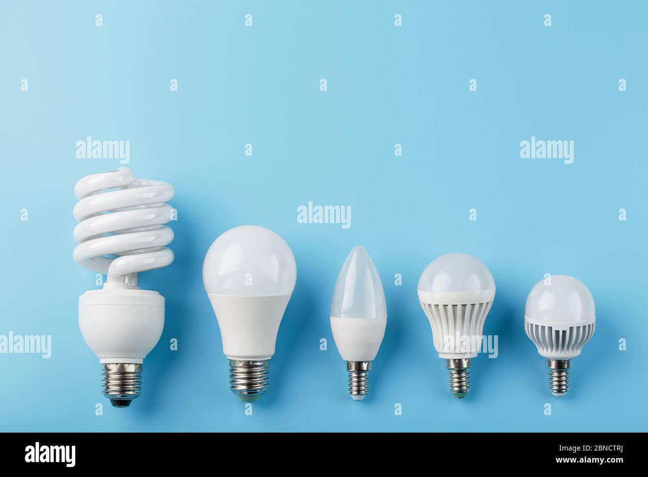 Energy-Saving light bulbs are arranged in a row on a blue background ...