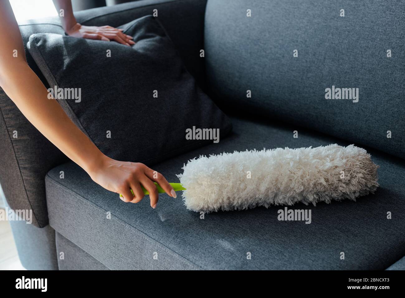cropped view of girl cleaning dust from sofa with duster Stock Photo ...