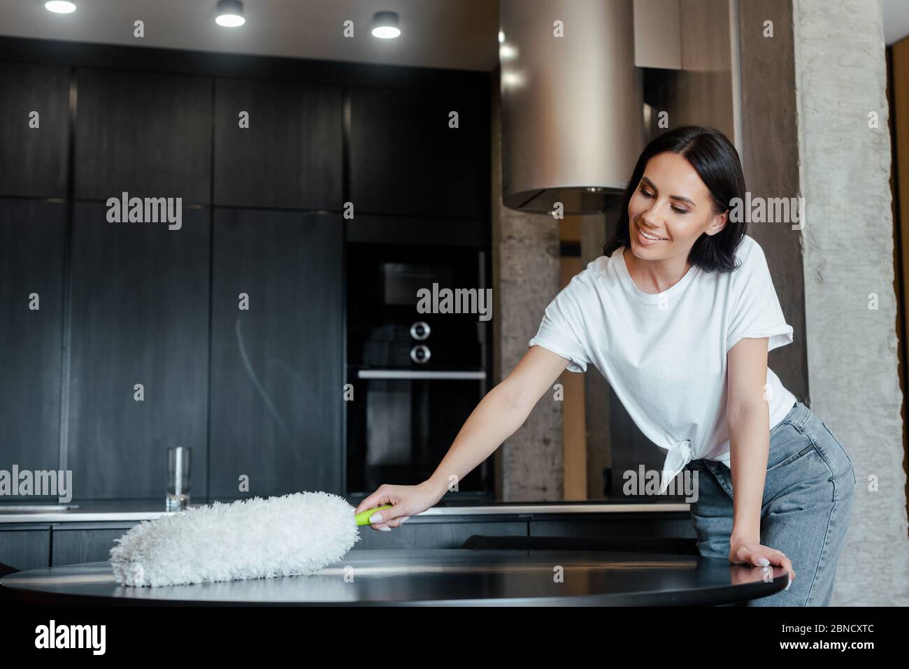 smiling girl cleaning dust from table with duster Stock Photo - Alamy