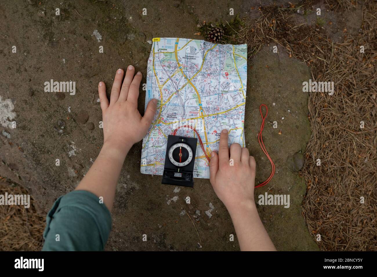 High angle shot of a human reading a map with a compass in the forest ...