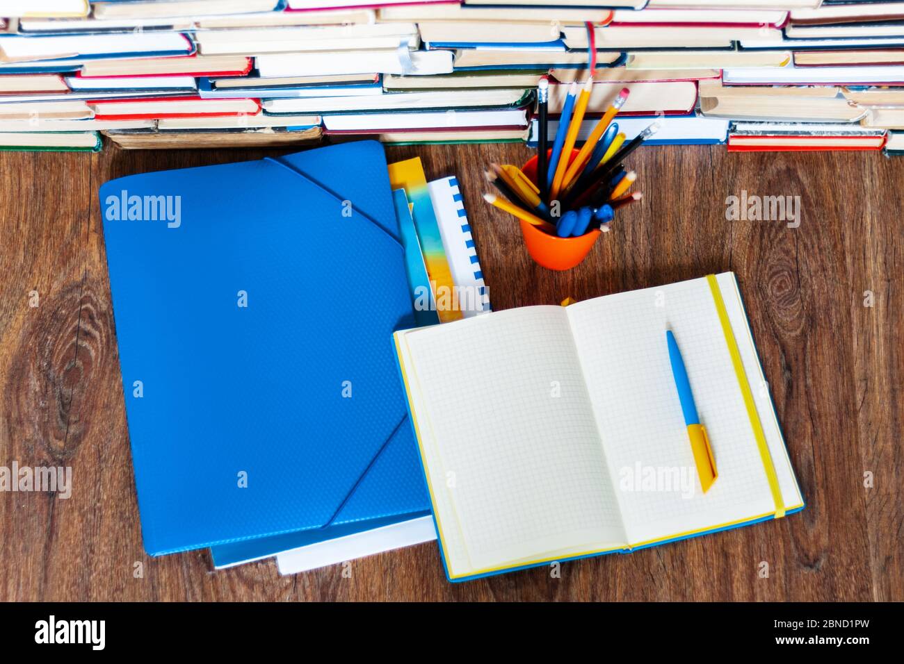 Open textbook, notebook, glasses, pencils in holder, plastic folder ...