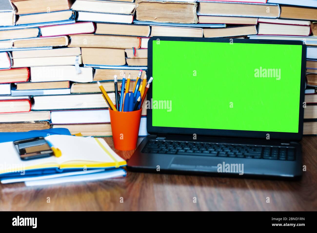 Textbook, notebook, green screen laptope and stack of books. Work from ...