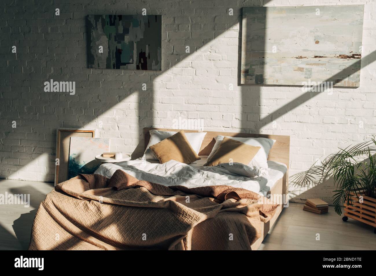 bedroom interior with bed, pillows and paintings in sunlight with ...