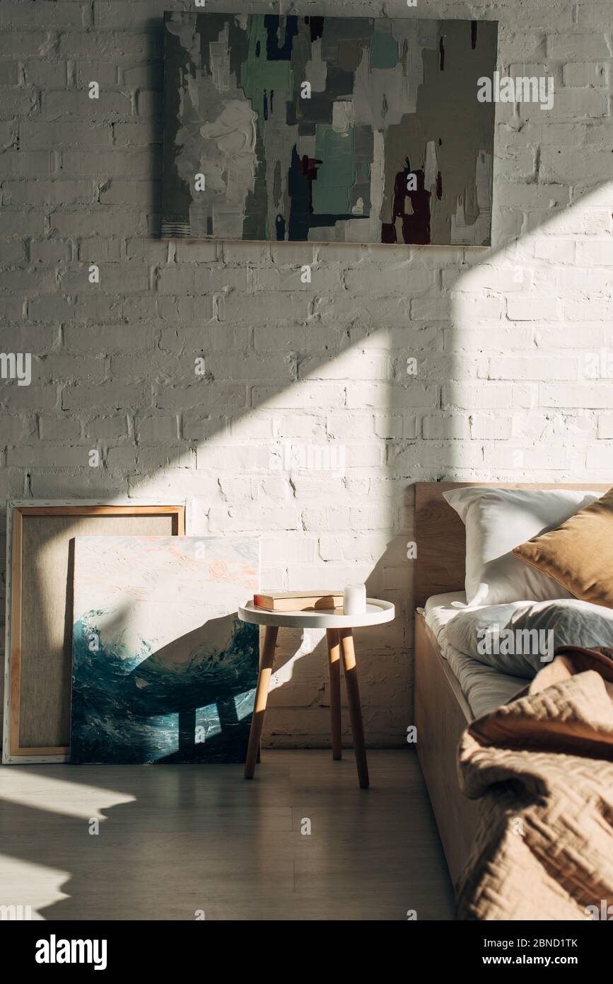 bedroom interior with pillows and paintings in sunlight with shadows ...