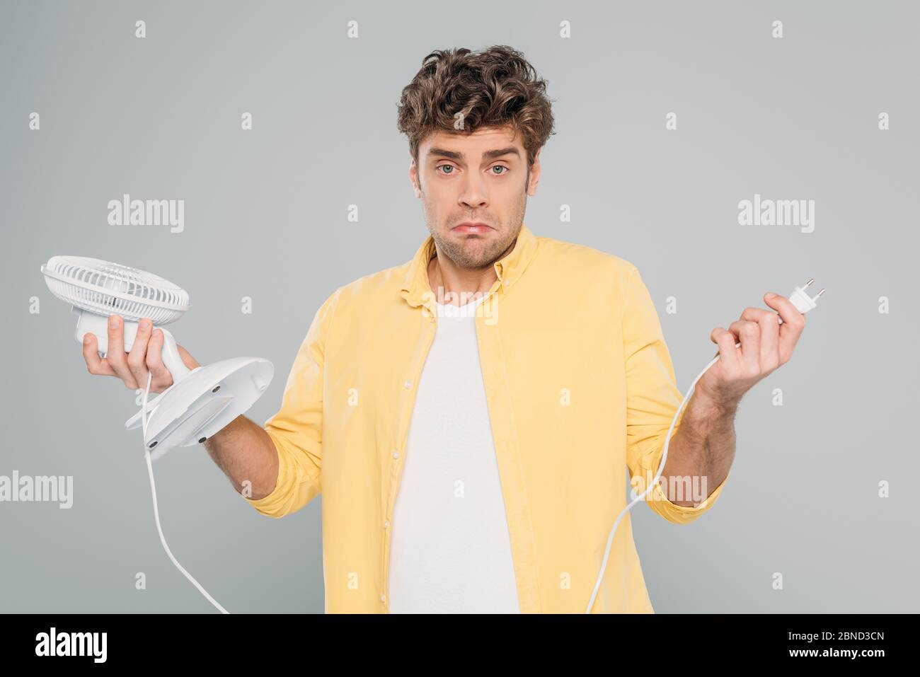 Front view of confused man with desk fan looking at camera isolated on ...