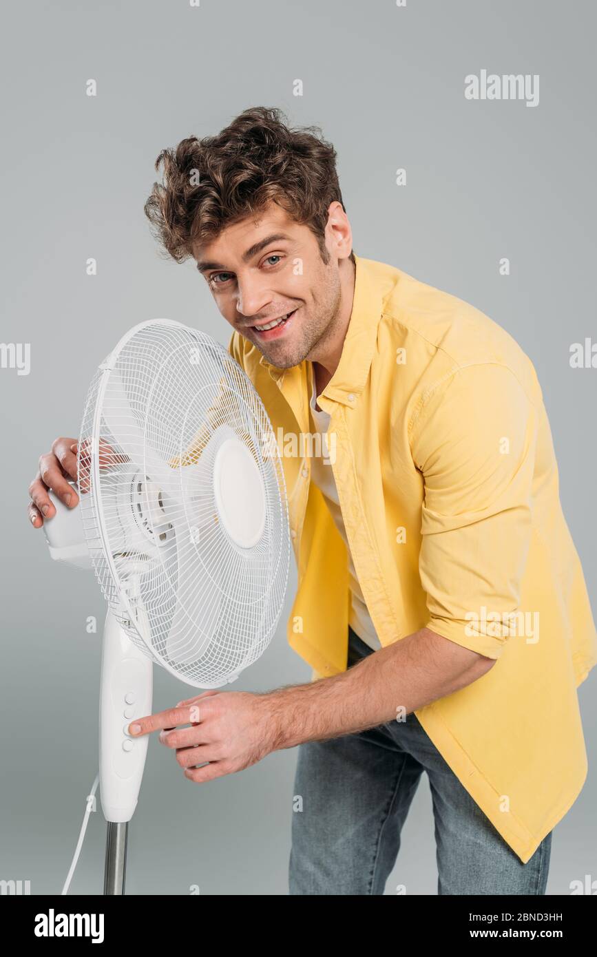 Man turning on electric fan, smiling and looking at camera isolated on ...