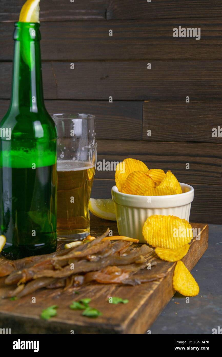 Dried carp fish sticks with beer, lemon and potato chips on dark wooden ...
