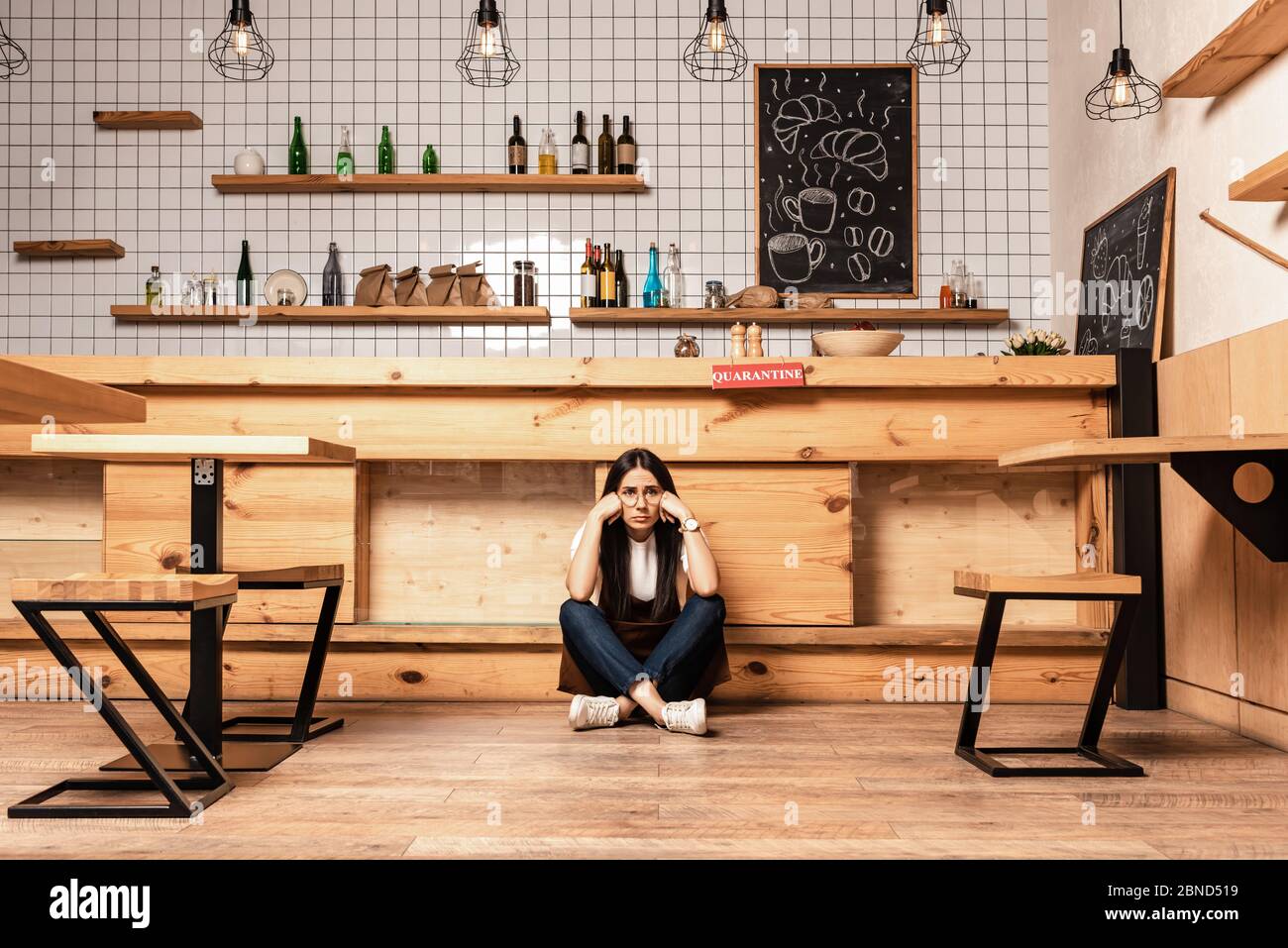 Cafe owner with crossed legs sitting on floor near table Stock Photo ...