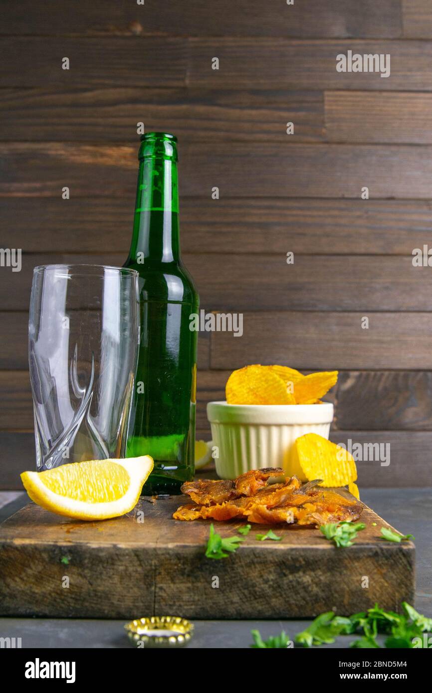 Dried perch with beer, lemon and potato chips on dark wooden board ...