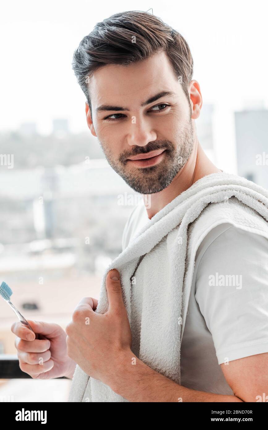 Side view of handsome man holding toothbrush and towel at home Stock ...