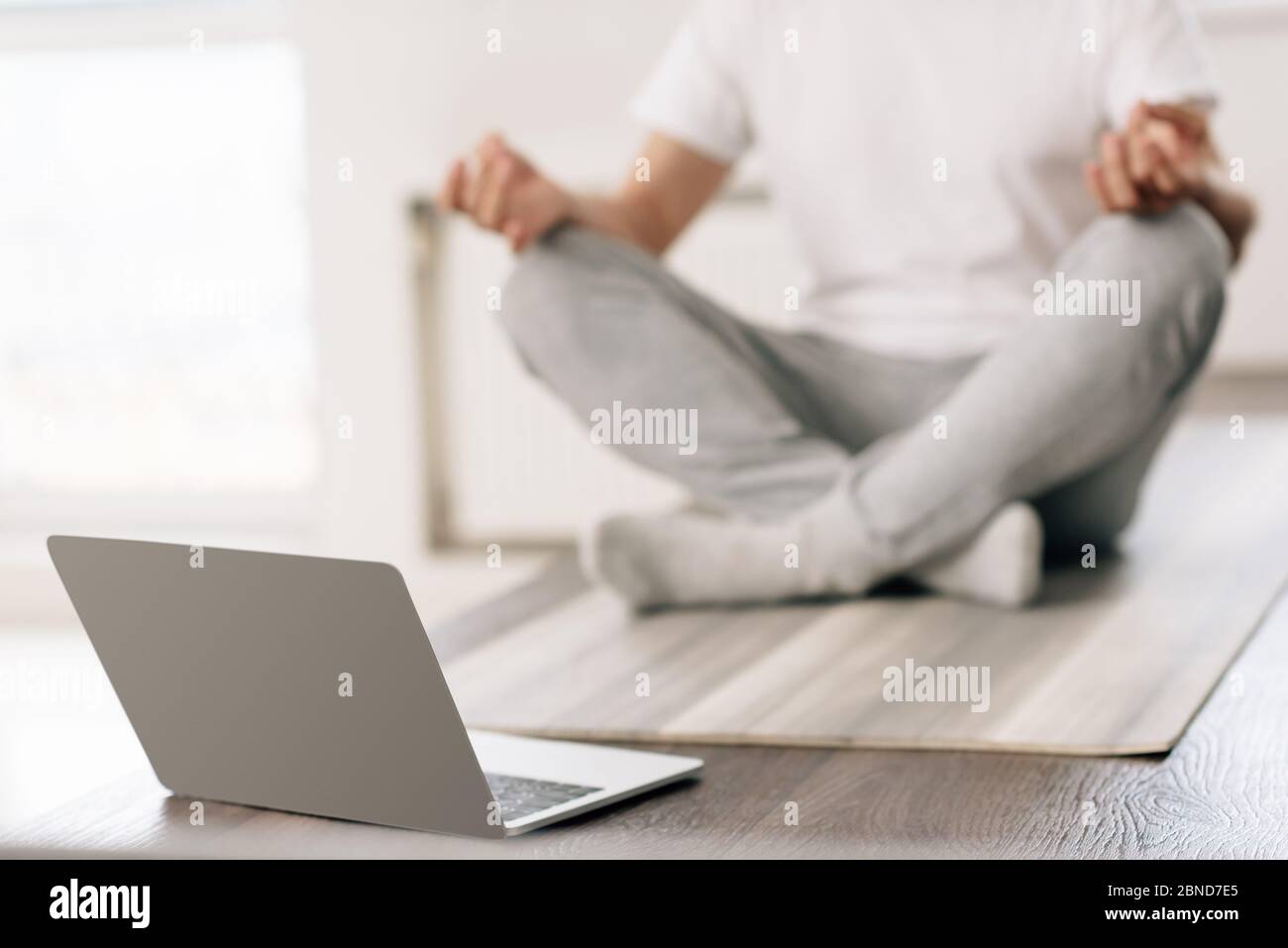 selective focus of laptop near man sitting in lotus pose at home Stock ...