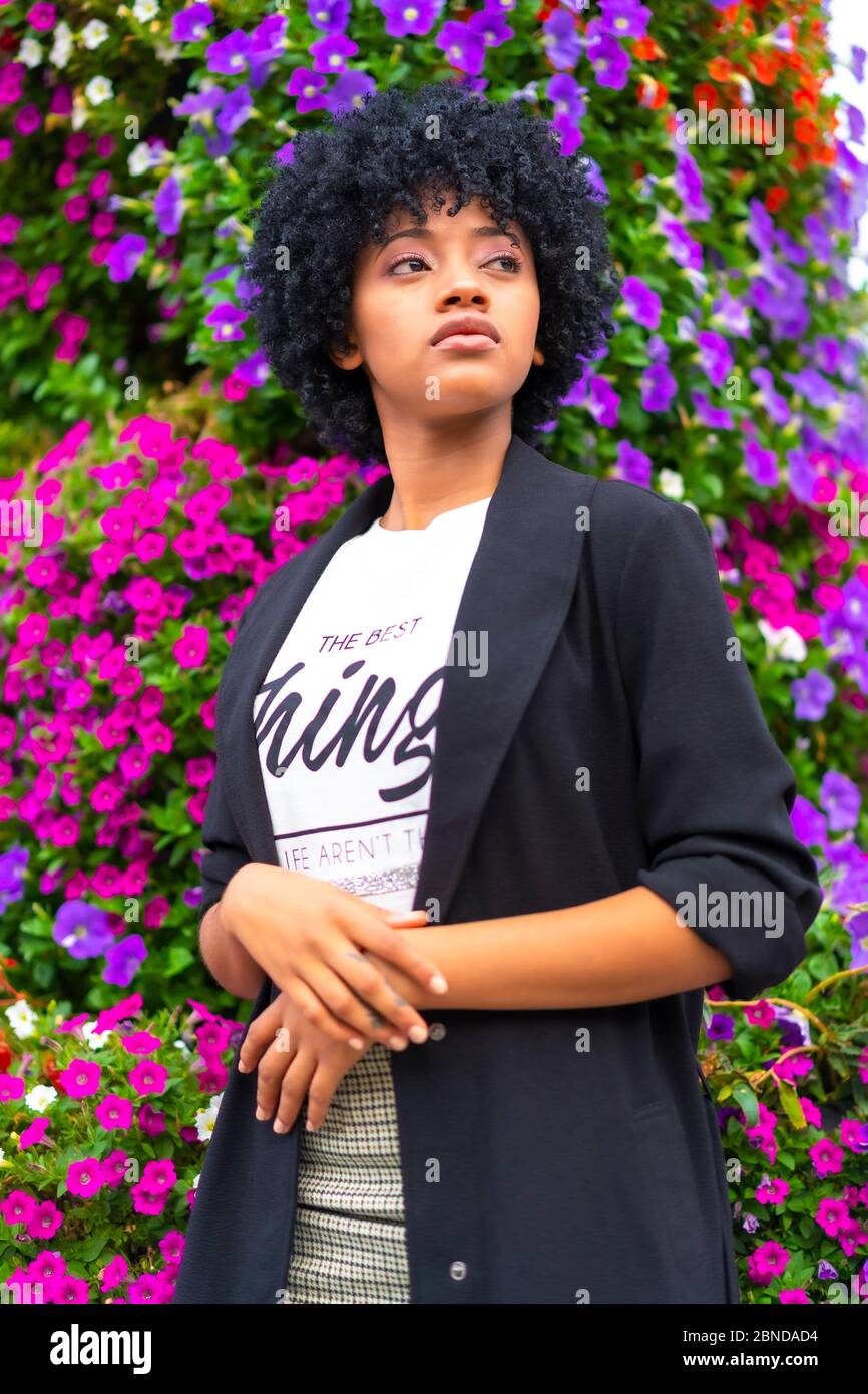 Street style, girl with afro hair in some city flowers Stock Photo - Alamy