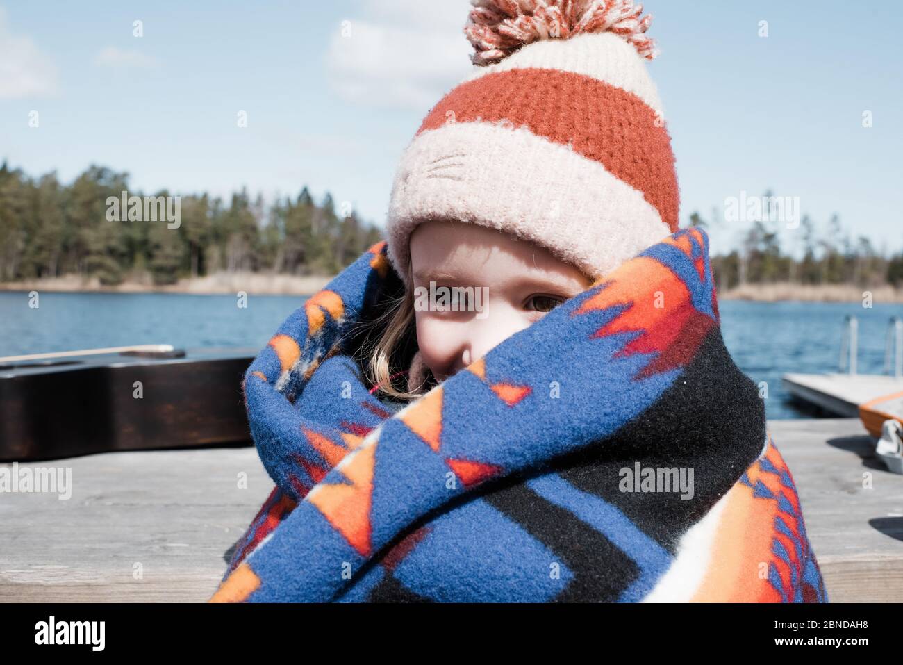young girl wrapped up in a blanket by the lake keeping warm Stock Photo ...