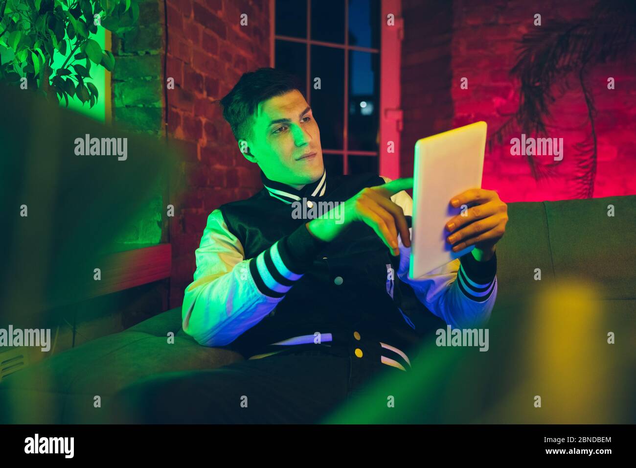 Pointing. Cinematic portrait of stylish man in neon lighted interior ...