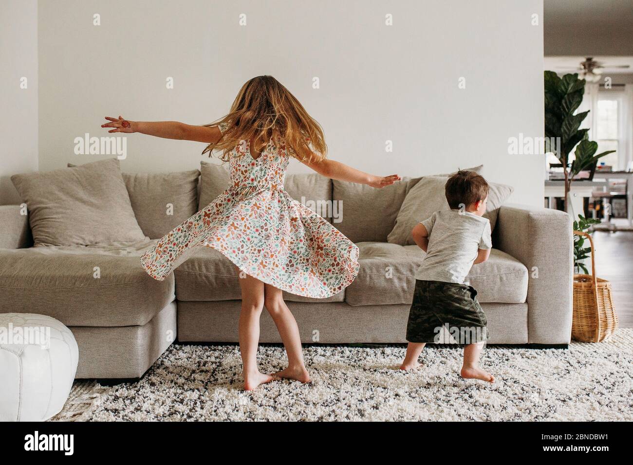 Siblings Twirling in Living Room Stock Photo - Alamy