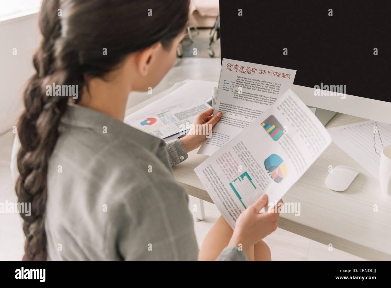 high angle view of freelancer looking at papers with graphs and charts ...